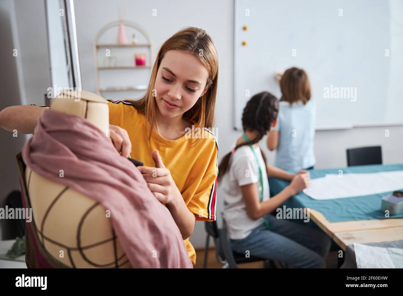Charming girl working with mannequin in sewing workshop Stock Photo - Alamy