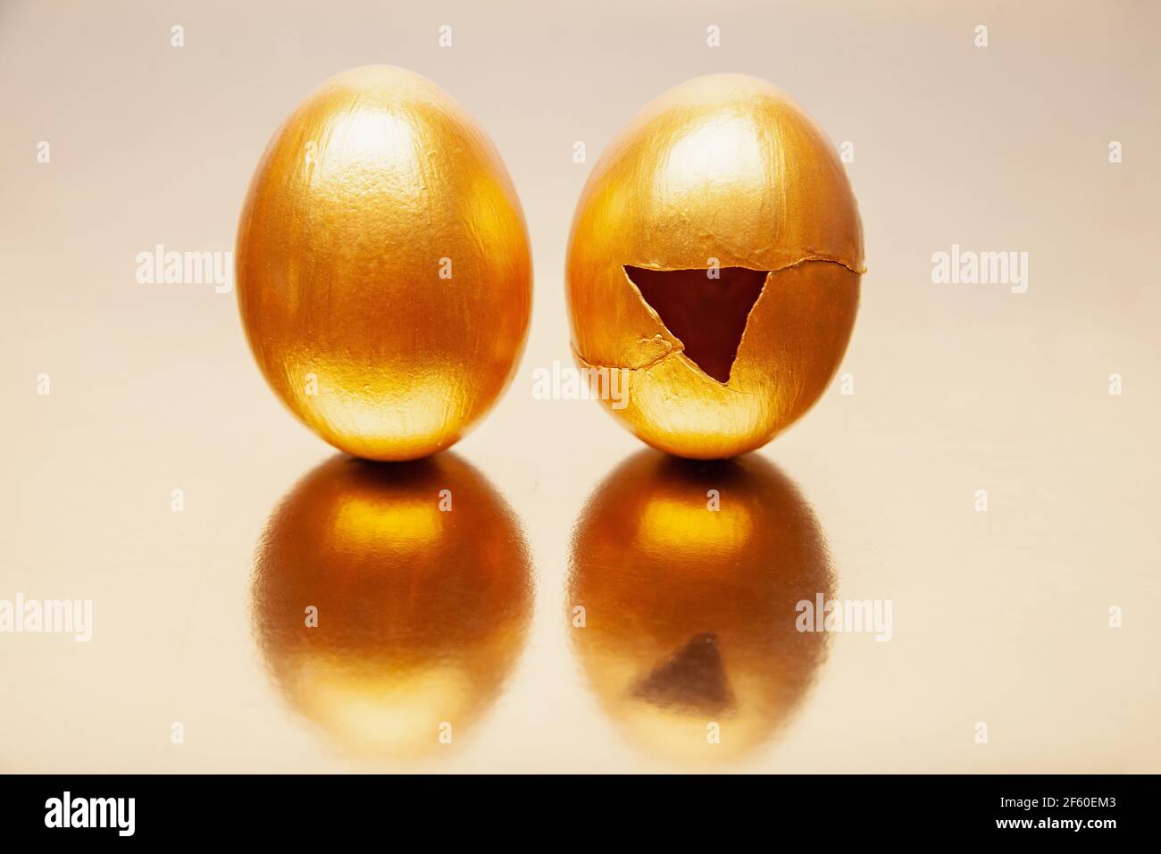 Whole and cracked Golden eggs placed on reflective table Stock Photo ...