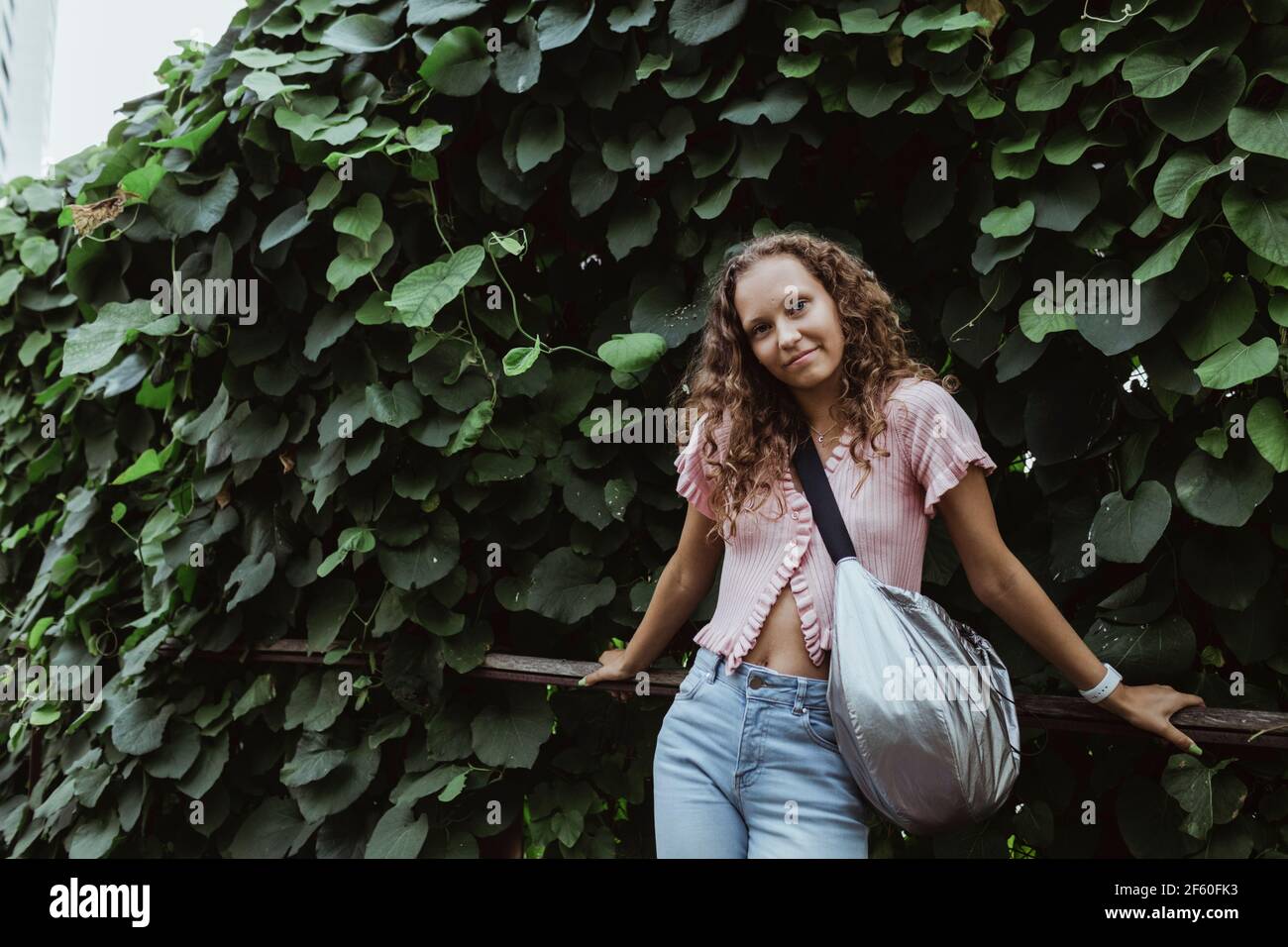 Portrait of woman leaning on railing against plants Stock Photo - Alamy