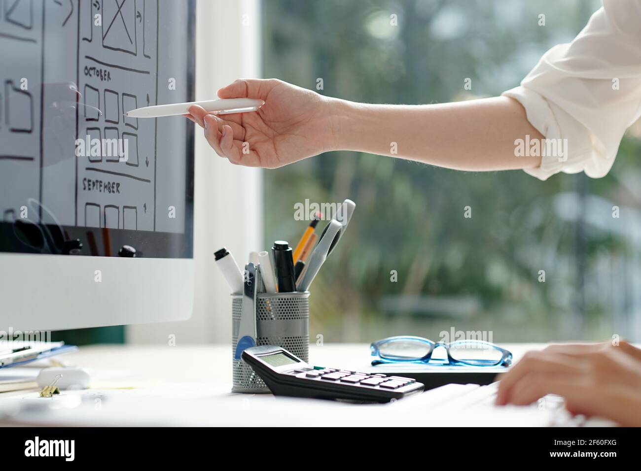 Project manager pointing at computer screen when asking UI designer ...