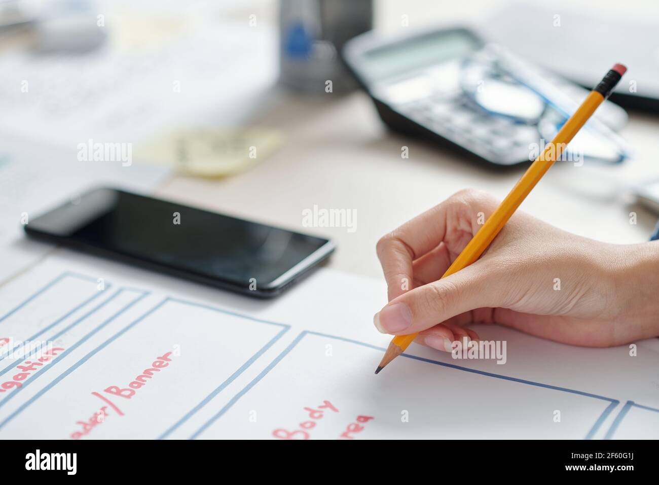 Hand of female UI designer drawing with pencil when creating mobile app ...