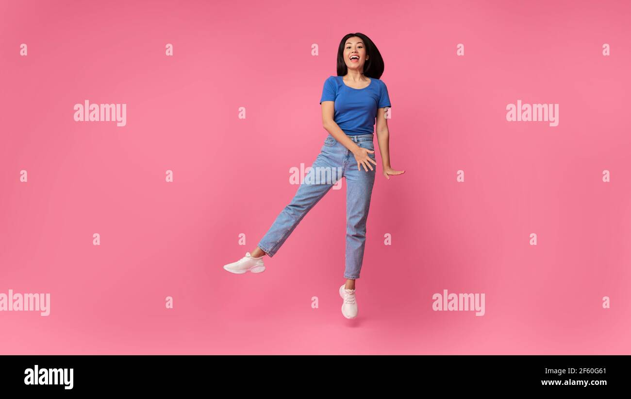 Happy young asian lady jumping at pink studio, panorama Stock Photo - Alamy