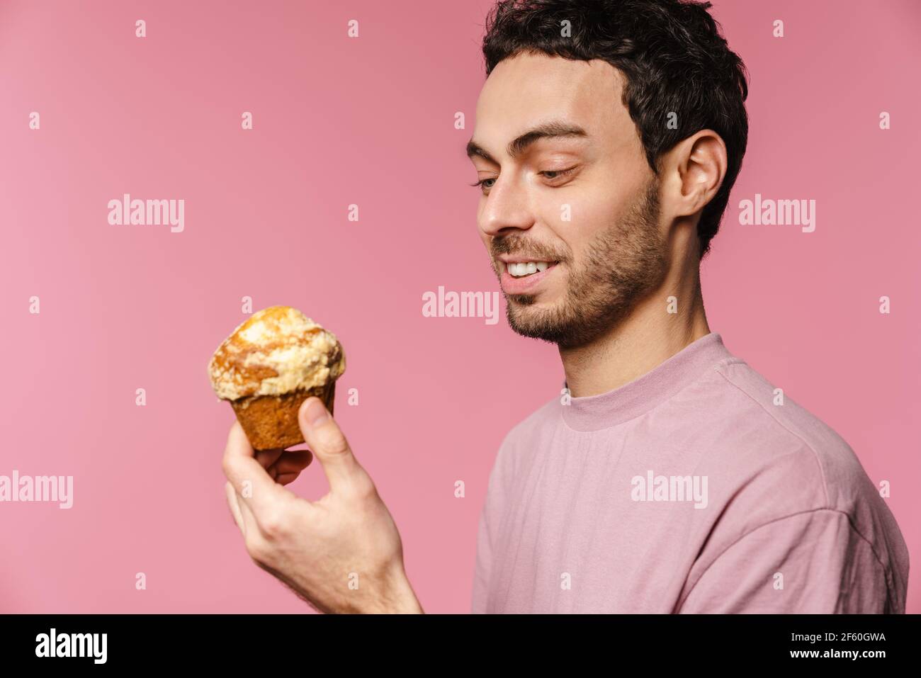 Pleased handsome guy smiling while posing with muffin isolated over ...