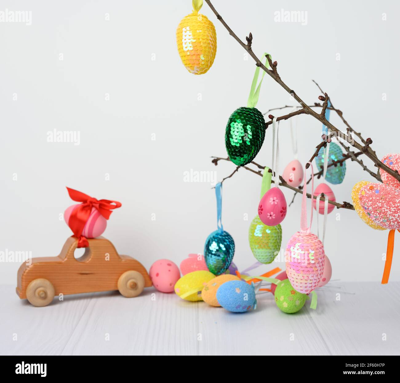 wooden toy car carrying a pink Easter egg fixed with a red ribbon ...