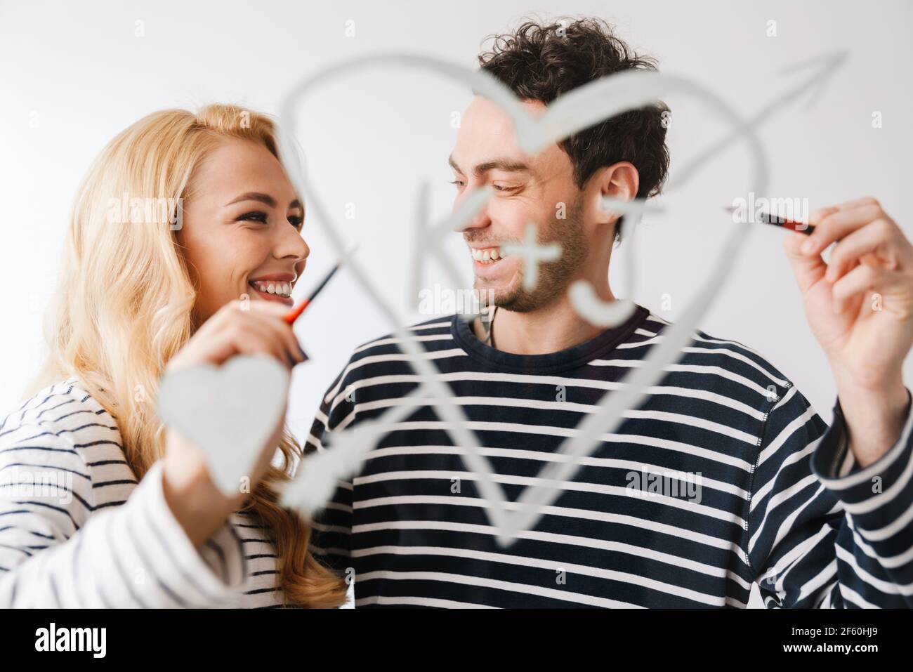 Beautiful smiling young couple in love drawing a heart symbol with ...