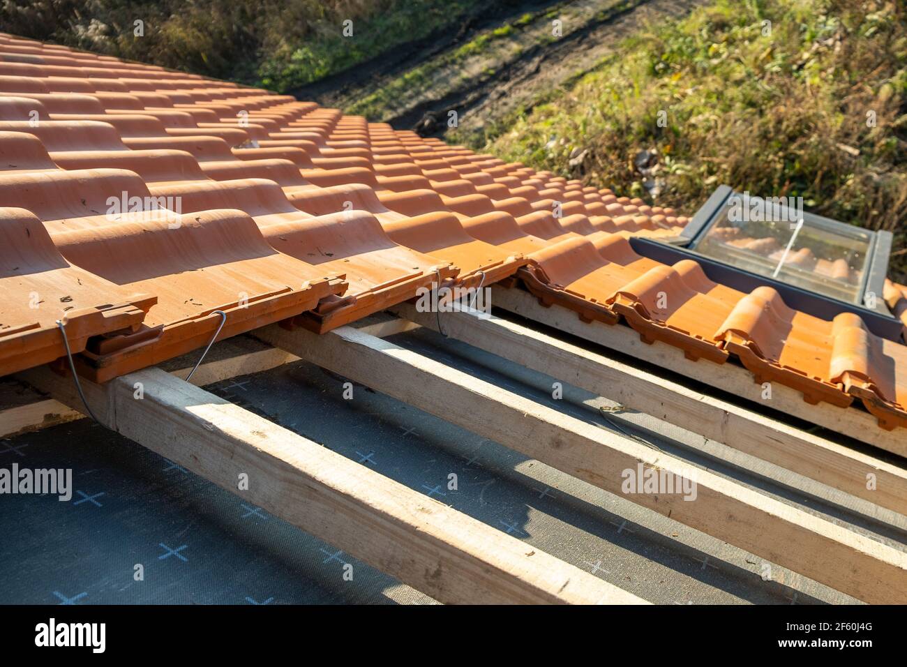 Overlapping rows of yellow ceramic roofing tiles mounted on wooden ...