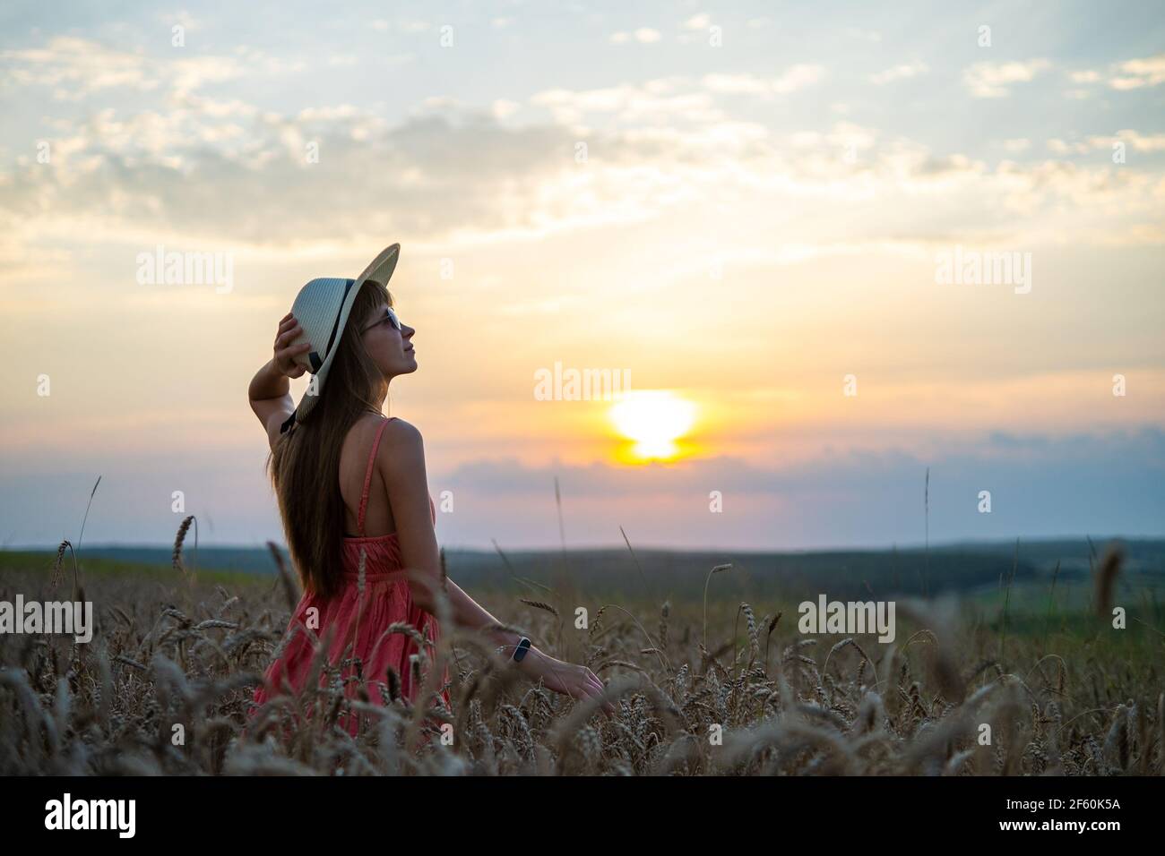Young happy woman in red summer dress and white straw hat walking on ...