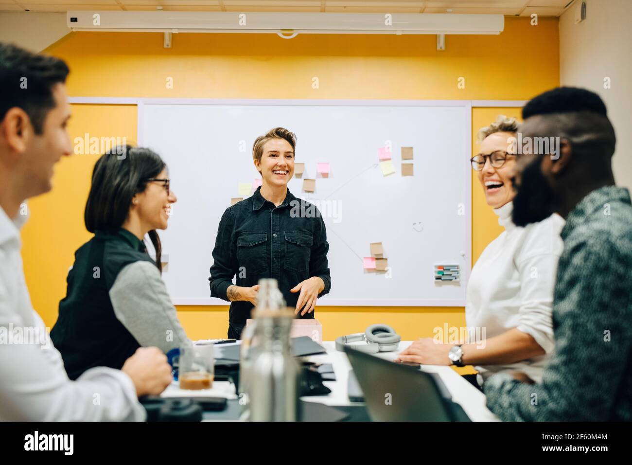 Business people laughing while discussing during meeting in board room ...
