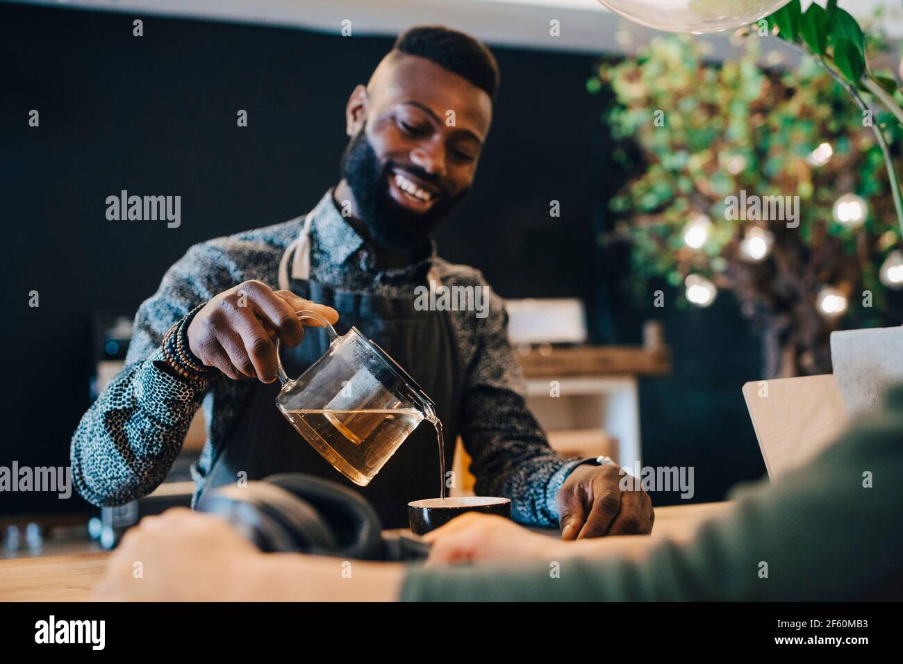 Smiling male owner pouring tea in cup at coffee shop Stock Photo - Alamy