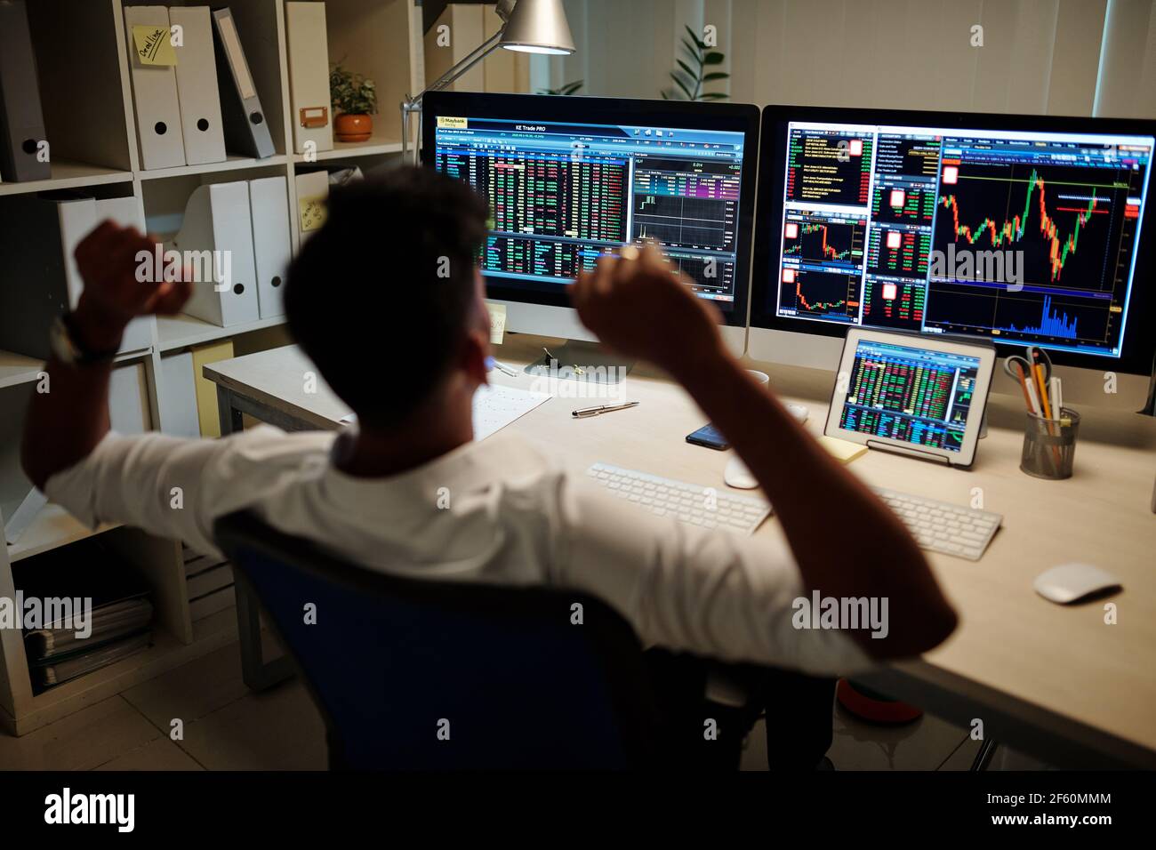 Trader stretching and relaxing in chair late at night after finishing ...
