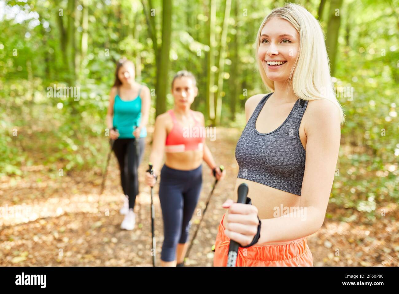 Three sporty women as a hiking group doing Nordic walking in nature ...