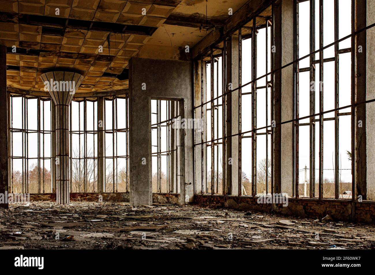 The ruined hall of an old building with wide windows. Broken glass on ...