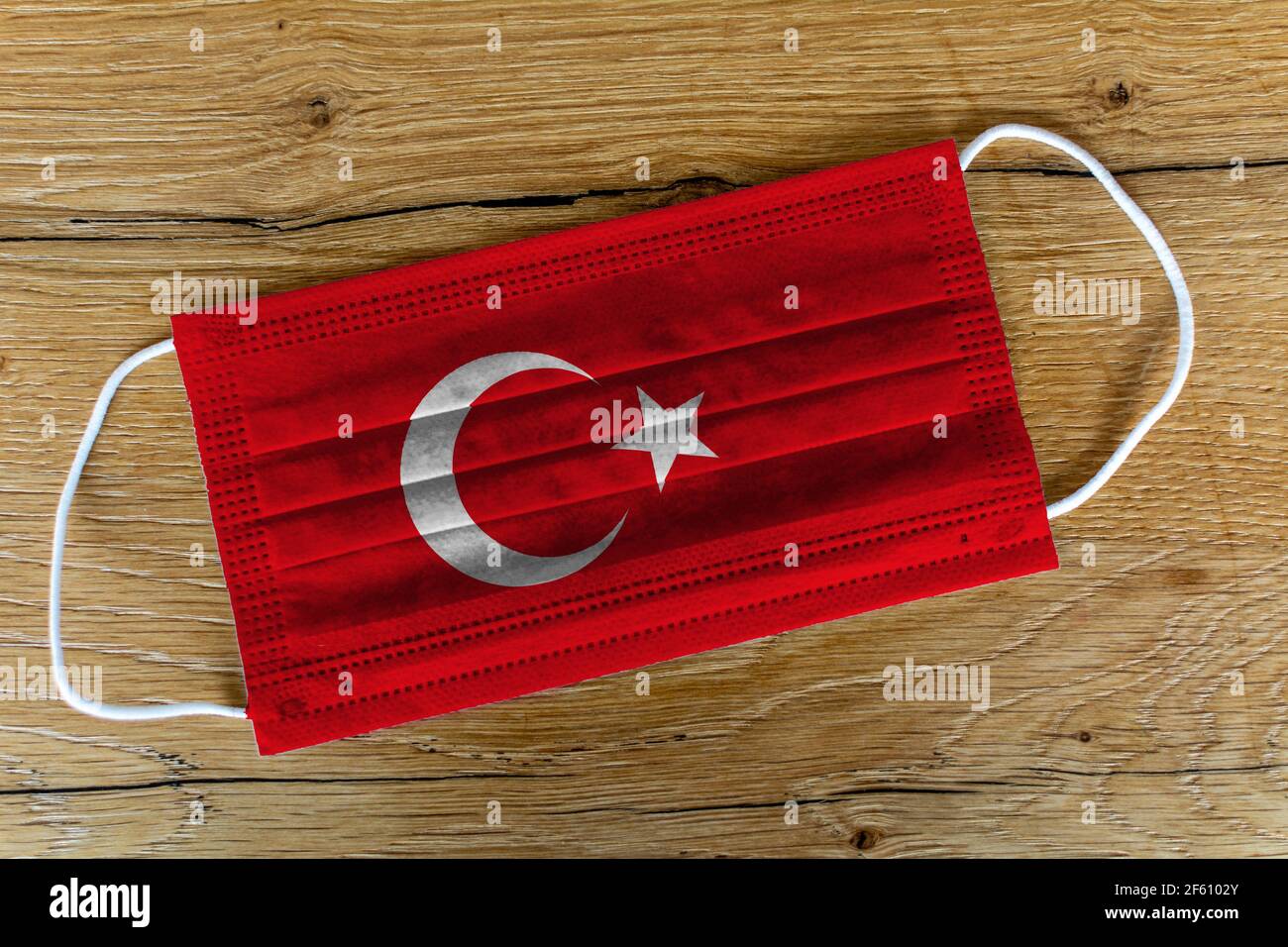 A surgical face mask with the painted flag of Turkey on a wooden ...