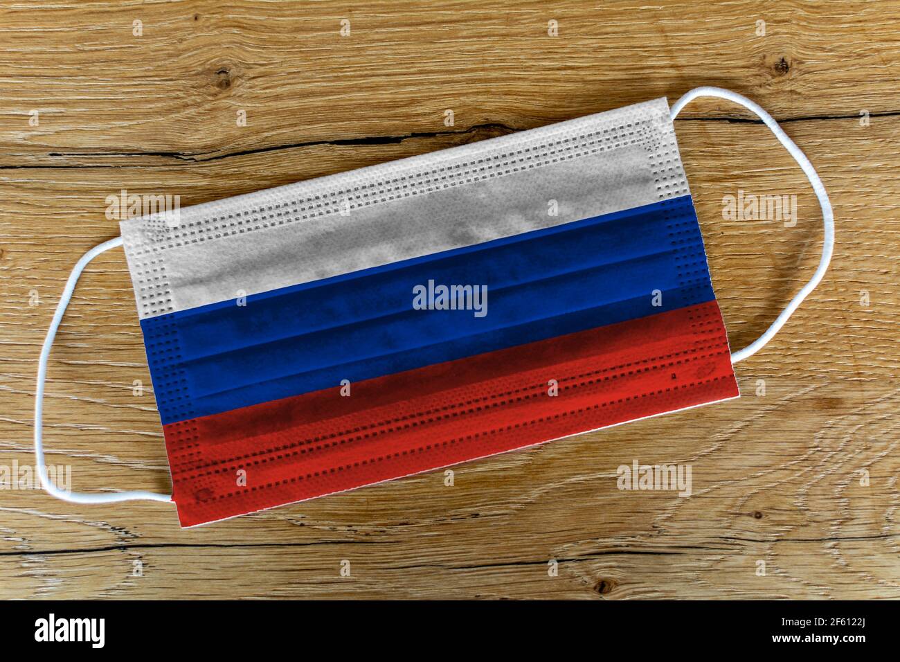 A surgical face mask with the painted flag of Russia on a wooden ...