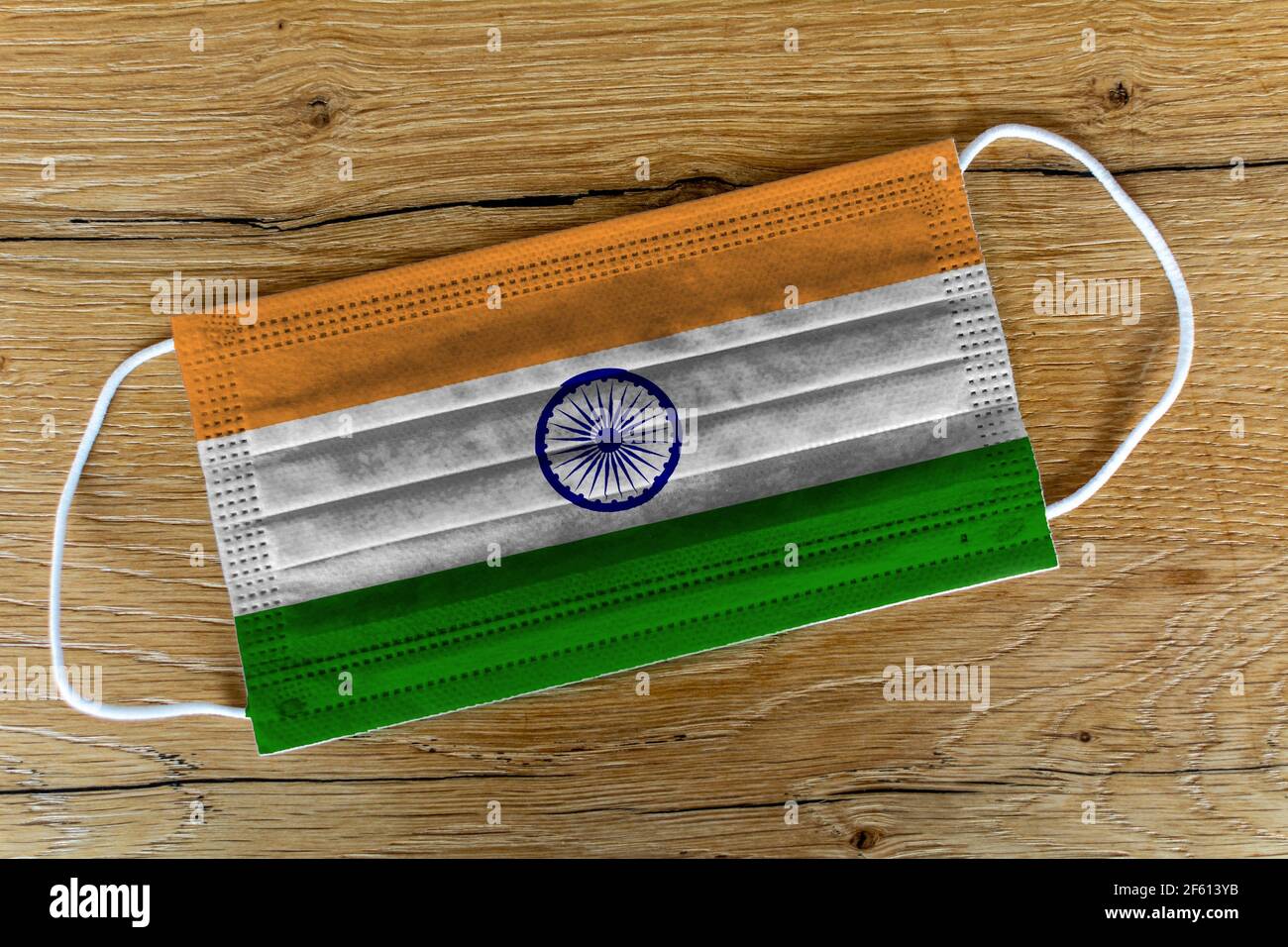 A surgical face mask with the painted flag of India on a wooden ...