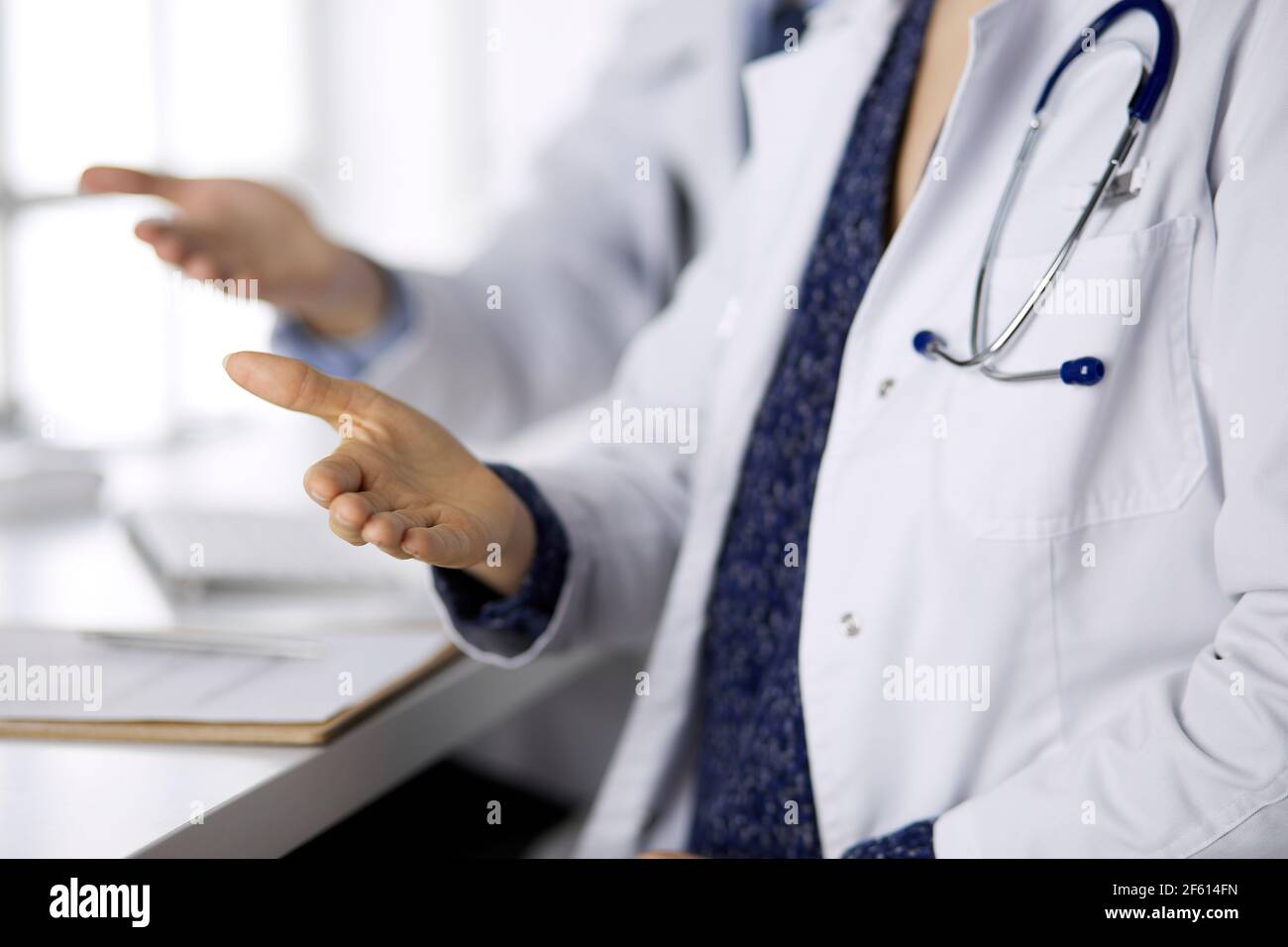 Two doctors sitting and offering helping hand for shaking hand or ...