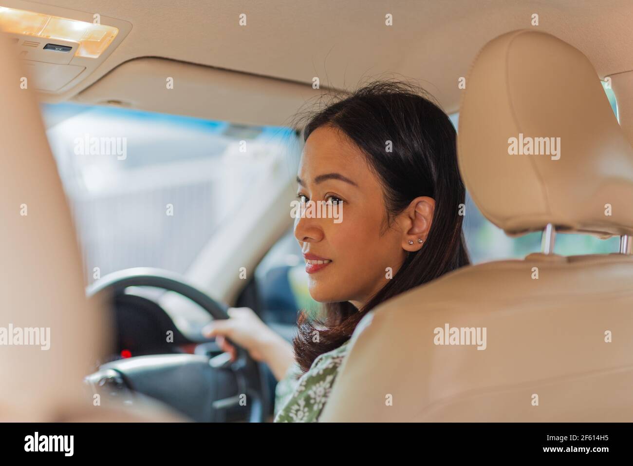 Woman looking over her shoulder while driving a car Stock Photo - Alamy