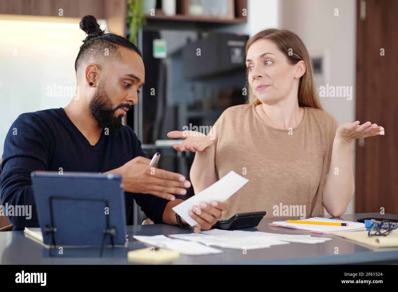 Serious man showing unpaid bill to confused wife when they are ...