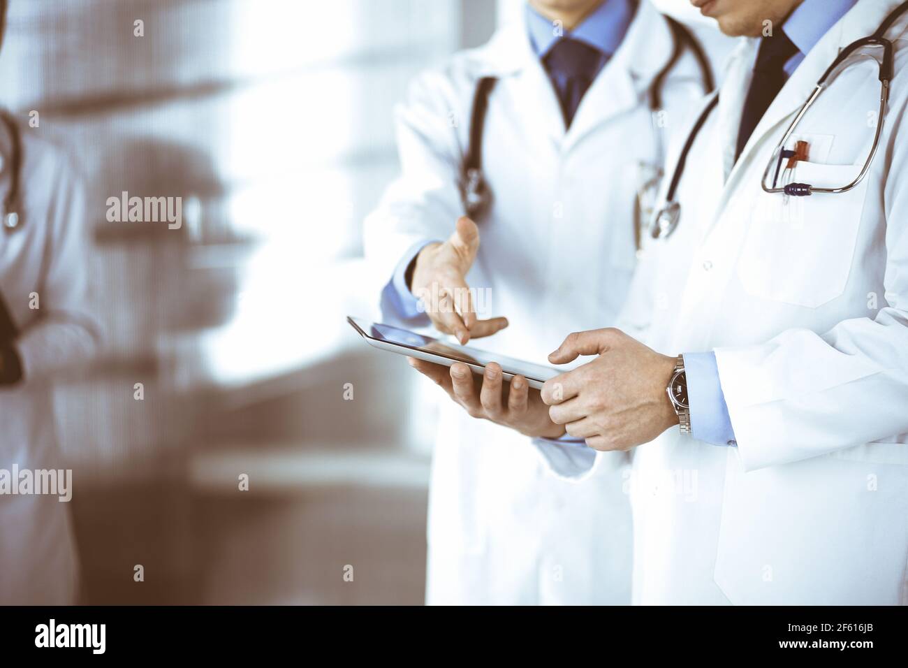 Group of unknown doctors use a computer tablet to check up some medical ...