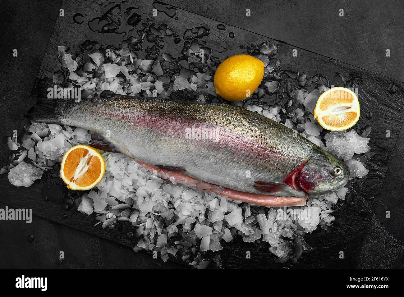 Raw fresh organic dorado or sea bream on ice cubes over black slate ...