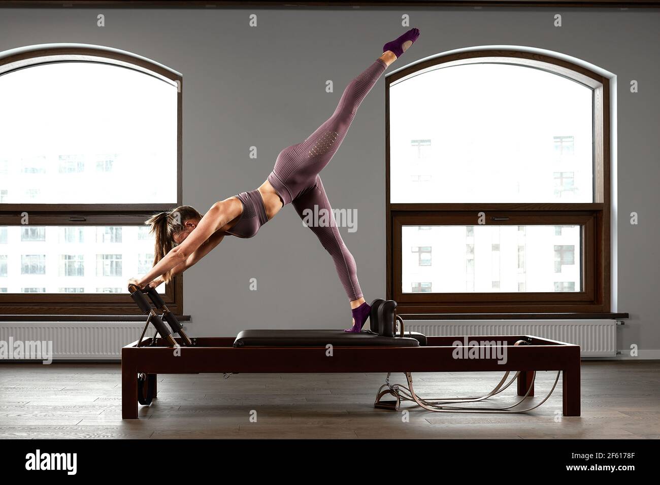 Young girl doing pilates exercises with a reformer bed. Beautiful slim ...