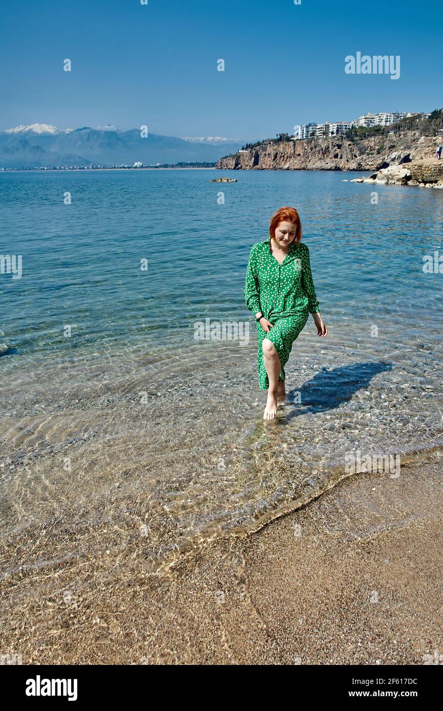 Young european woman walks barefoot on beach in Antalya early spring ...