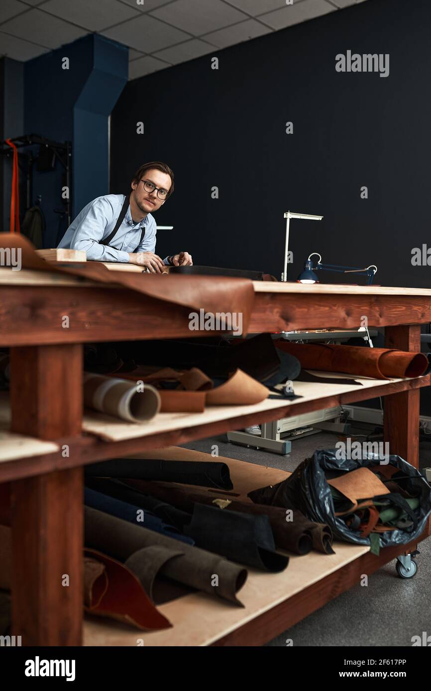 Skilled leather manufacture worker cutting some samples in workshop ...