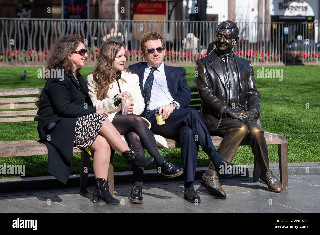 People sit and chat on a bench next to the Mr Bean statue in Leicester ...