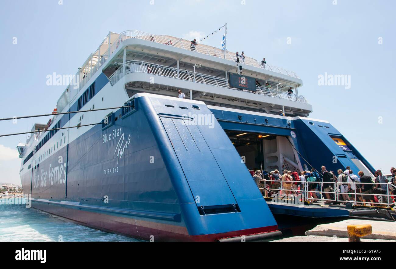 A ferry ship with an open ramp and a group of passengers is boarding ...