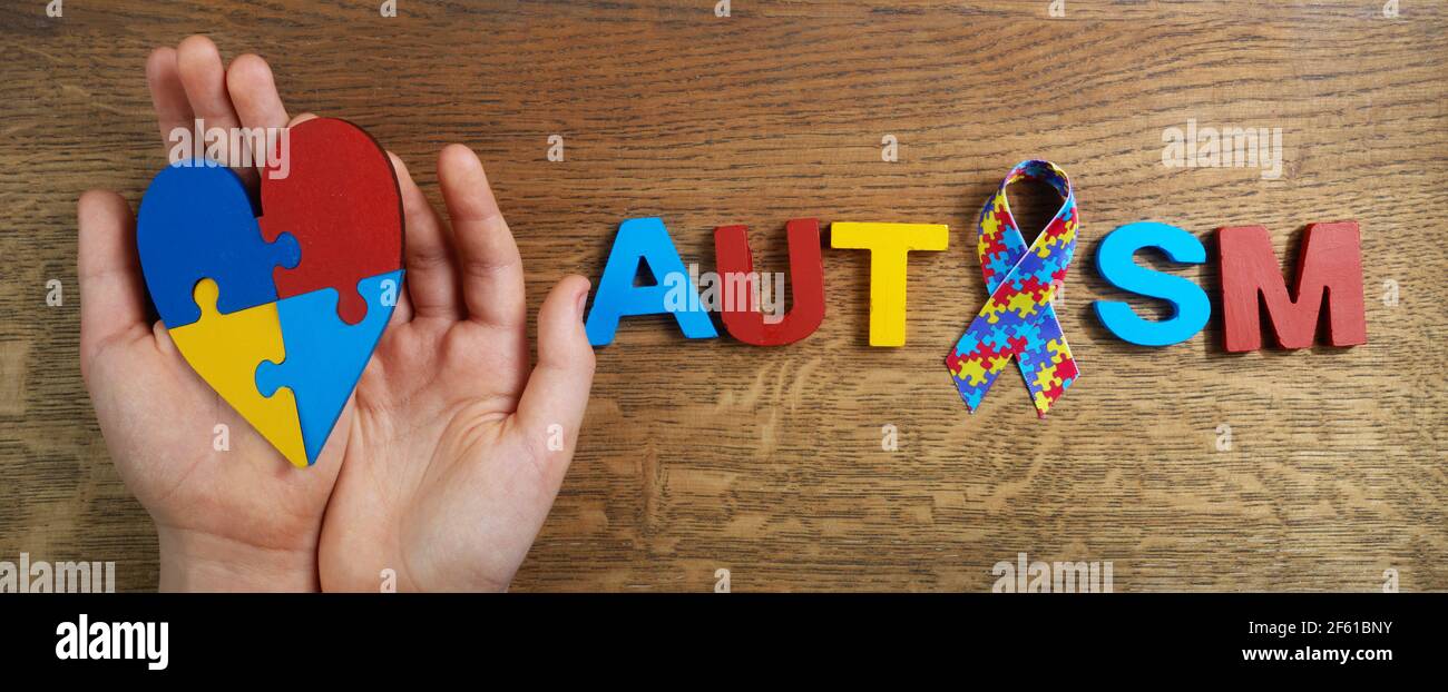 Autistic boy hands holding heart shapeed puzzle with word autism and ...