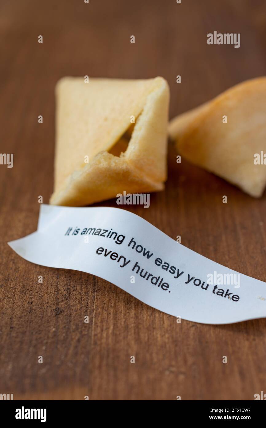 Close-up of open fortune cookie with message, on wooden table ...
