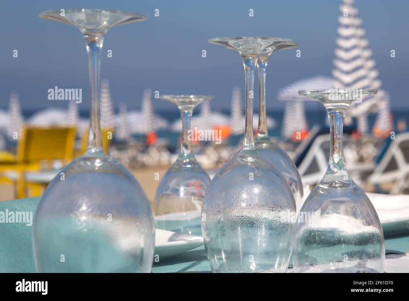 Inverted glasses on the table in the beach cafe a little sweaty, lit by ...