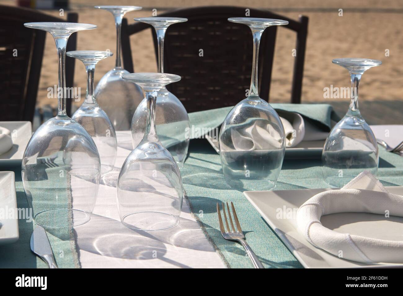 Inverted glasses on the table in the beach cafe a little sweaty, lit by ...