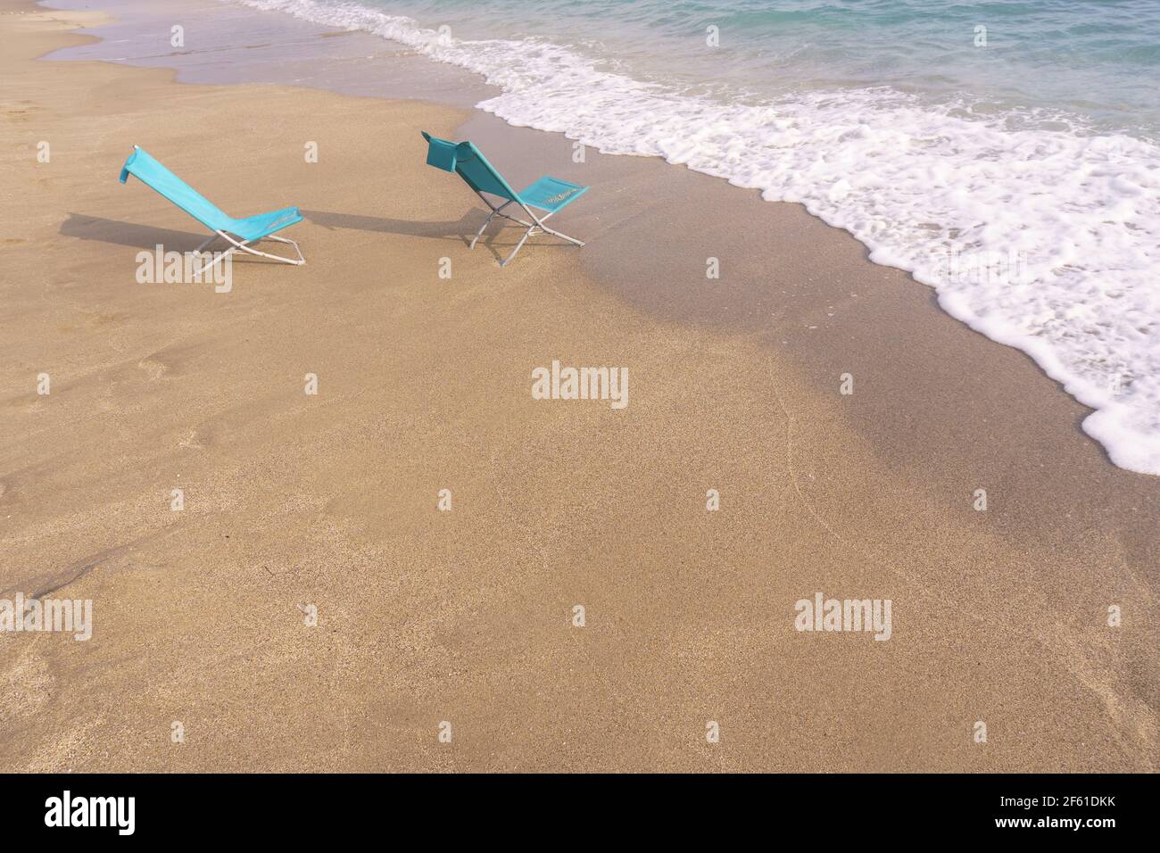 Two turquoise chaise Lounges on the sandy beach Stock Photo - Alamy