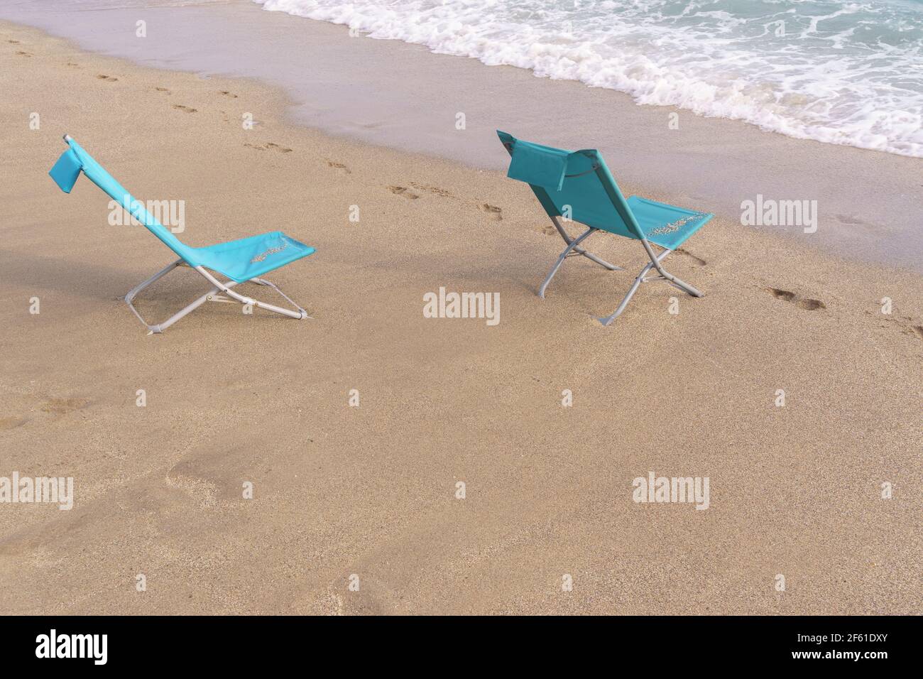 Two turquoise chaise Lounges on the sandy beach Stock Photo - Alamy
