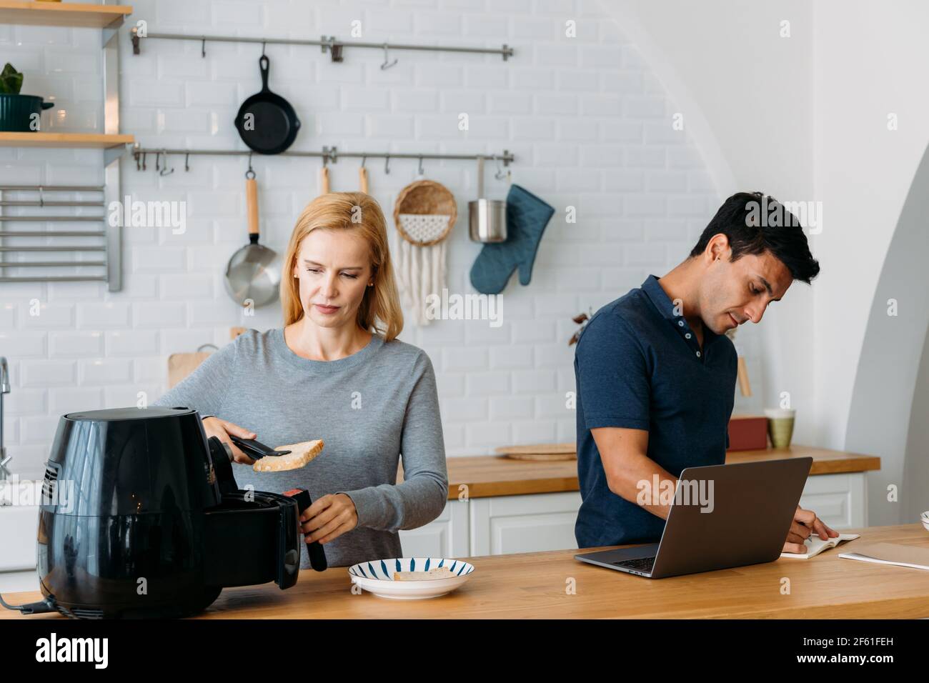 Beautiful young caucasian wife in kitchen cooking healthy oil free meal ...