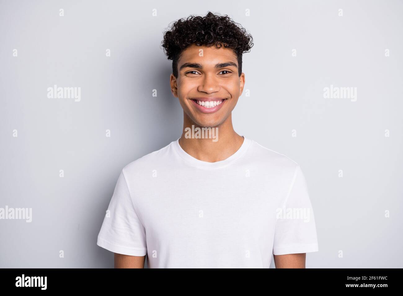 Portrait Of Brunet Optimistic Curly Guy Wear White T Shirt Isolated On