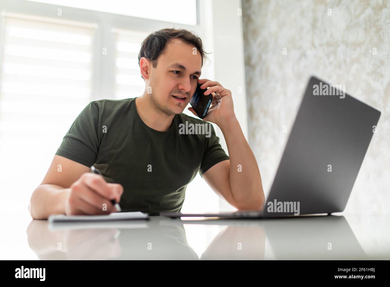 Handsome man calculate bills make notice using laptop and talking on ...