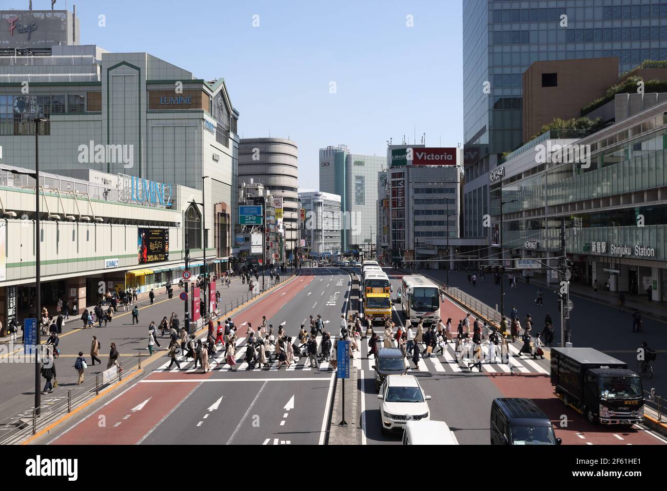 Tokyo, Japan. 24th Mar, 2021. Pedestrians cross in front of Shinjuku ...