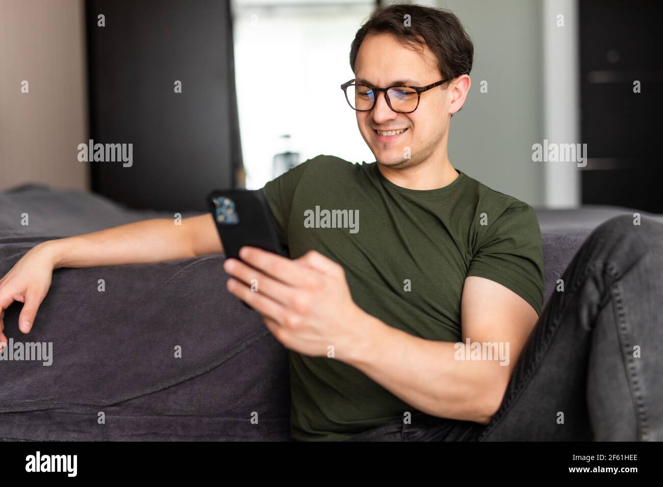 Happy, relaxed man at home using phone sitting on the floor Stock Photo ...