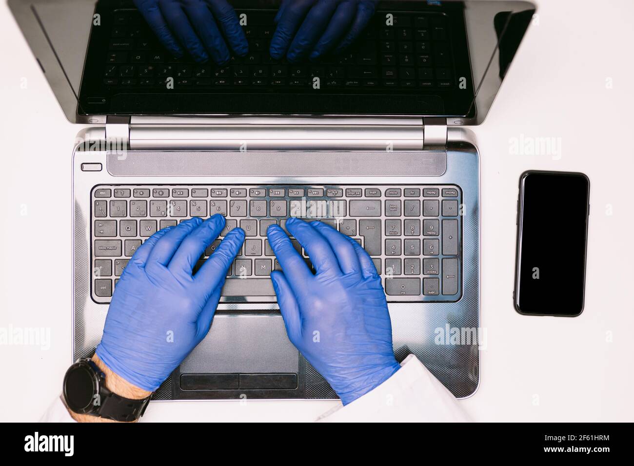 Aerial view of a laptop, doctor's hands with latex gloves typing with ...