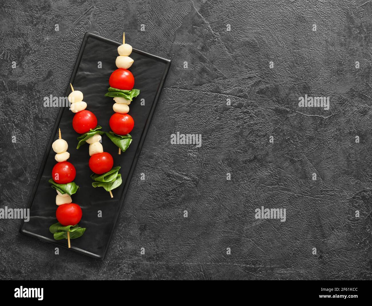 Sticks with mozzarella cheese, tomatoes and basil on dark background ...
