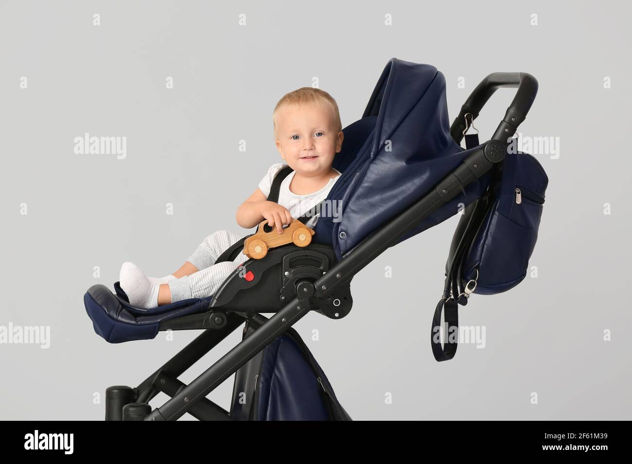Cute funny baby in stroller on grey background Stock Photo - Alamy
