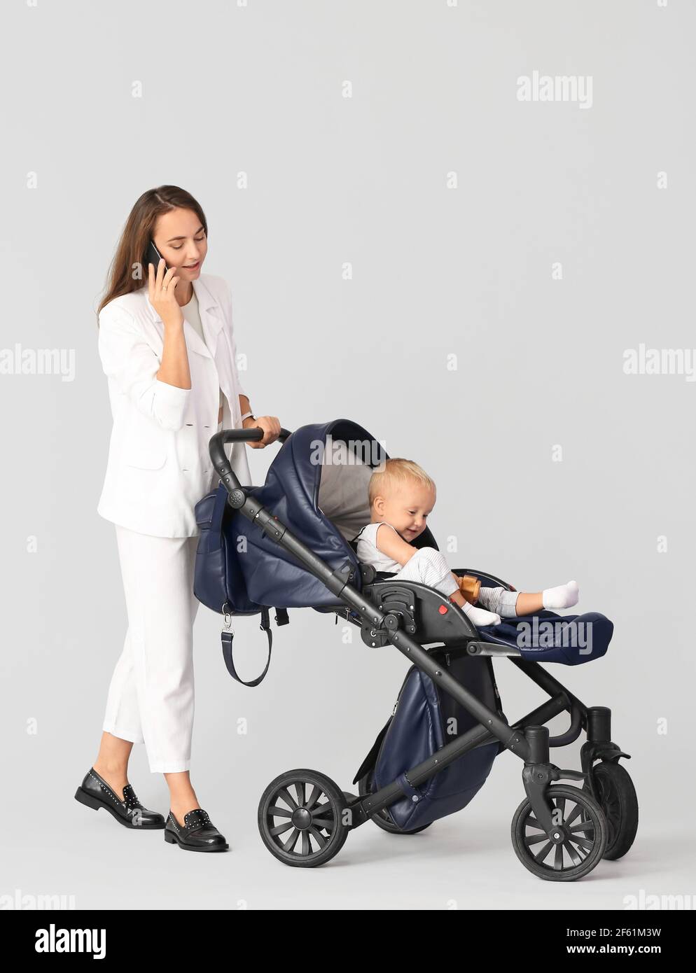 Woman and her cute baby in stroller on grey background Stock Photo - Alamy