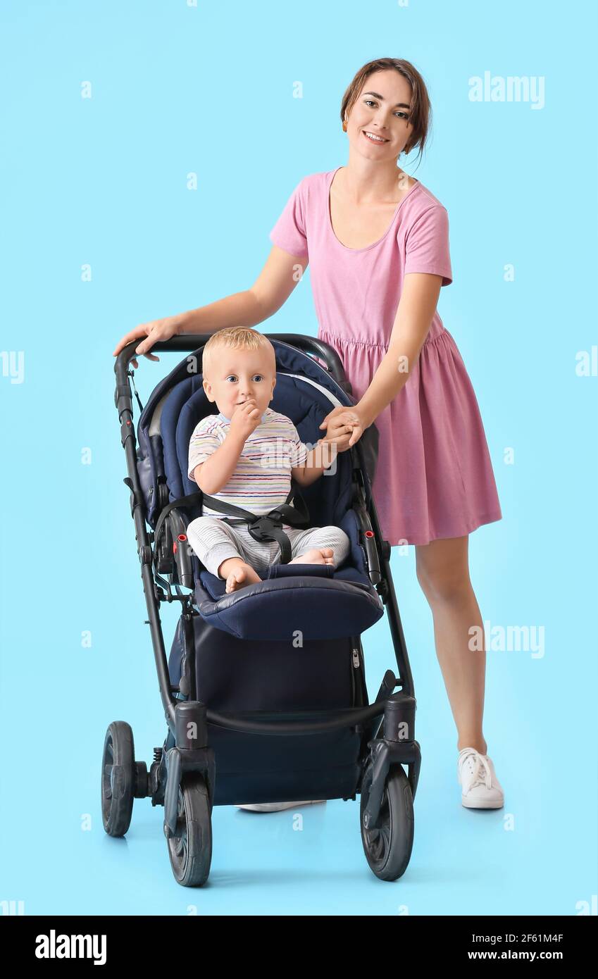 Woman and her cute baby in stroller on color background Stock Photo - Alamy
