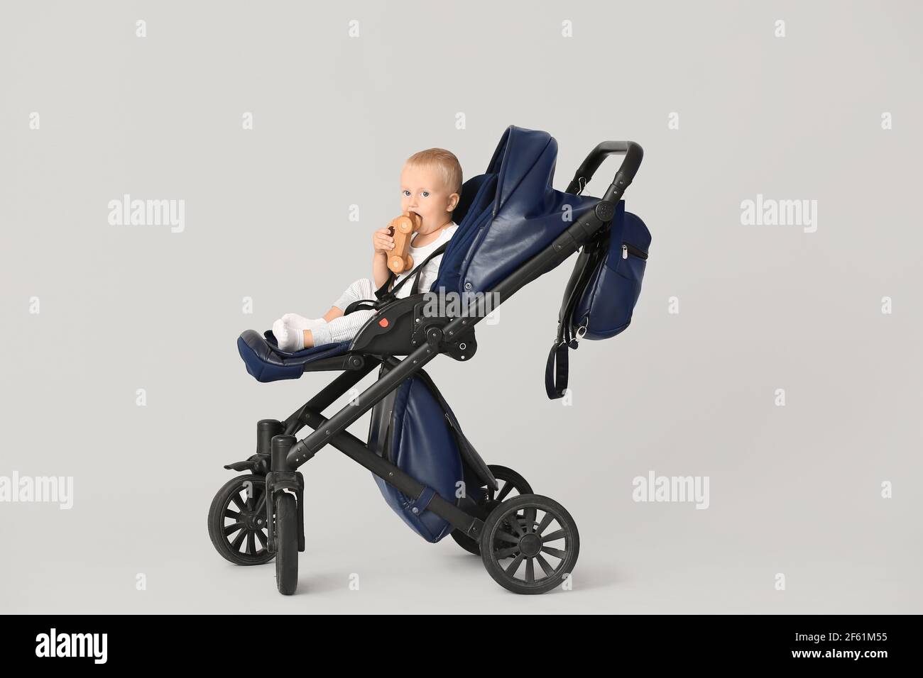 Cute funny baby in stroller on grey background Stock Photo - Alamy