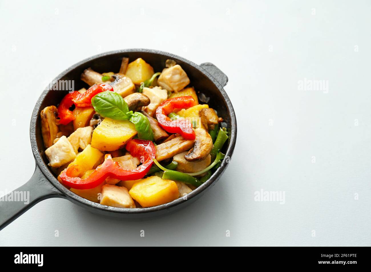 Frying pan with tasty vegetables and chicken on light background Stock ...