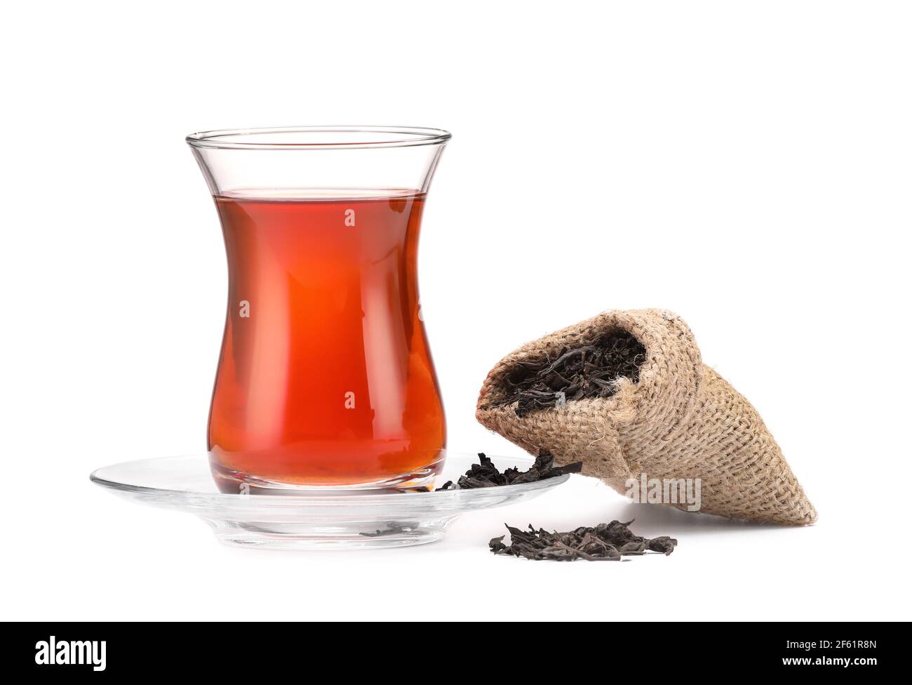 Glass of tasty Turkish tea and bag with dry leaves on white background ...