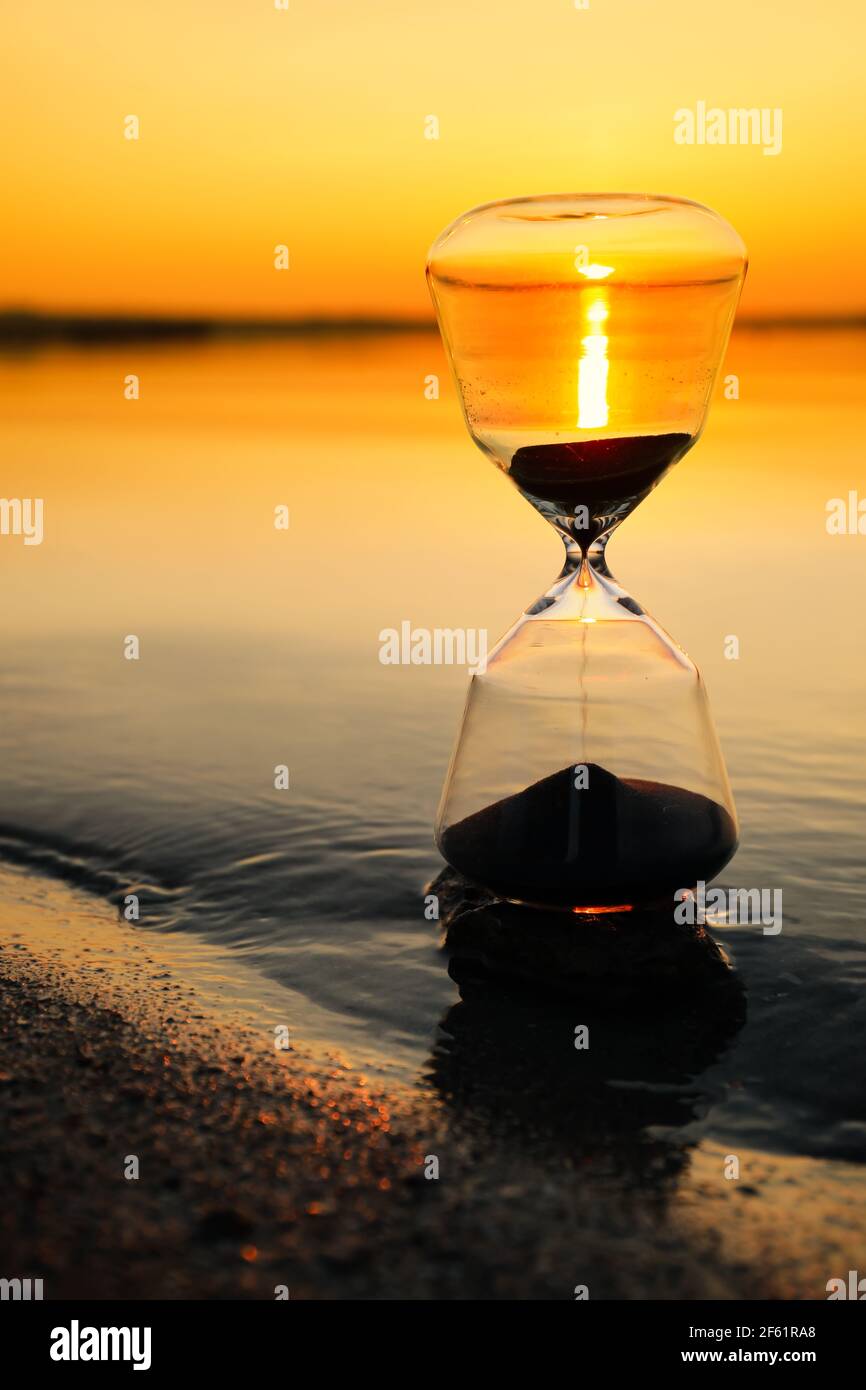 Stylish hourglass near river at sunset Stock Photo - Alamy