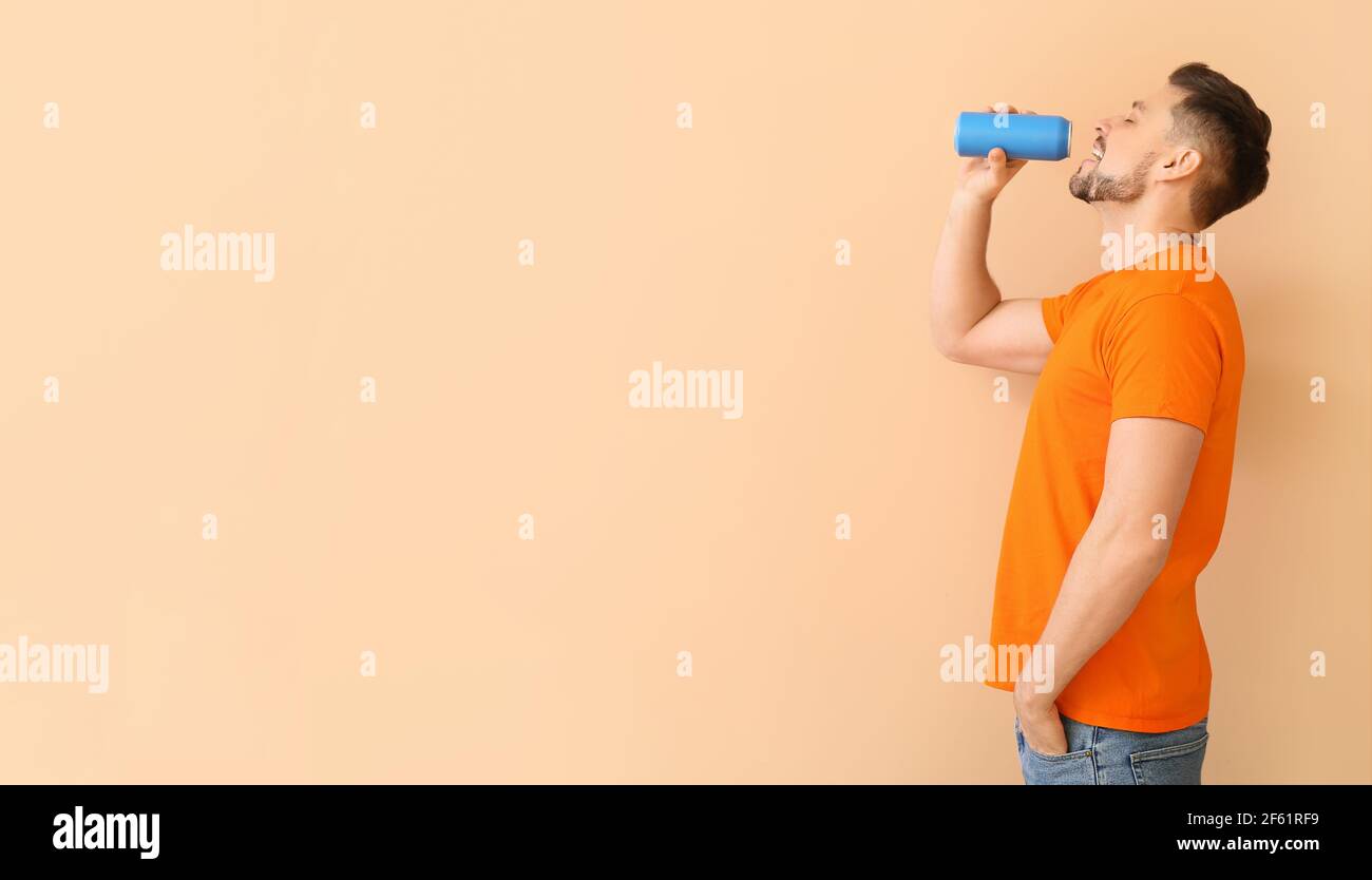 Handsome man drinking soda on color background Stock Photo - Alamy